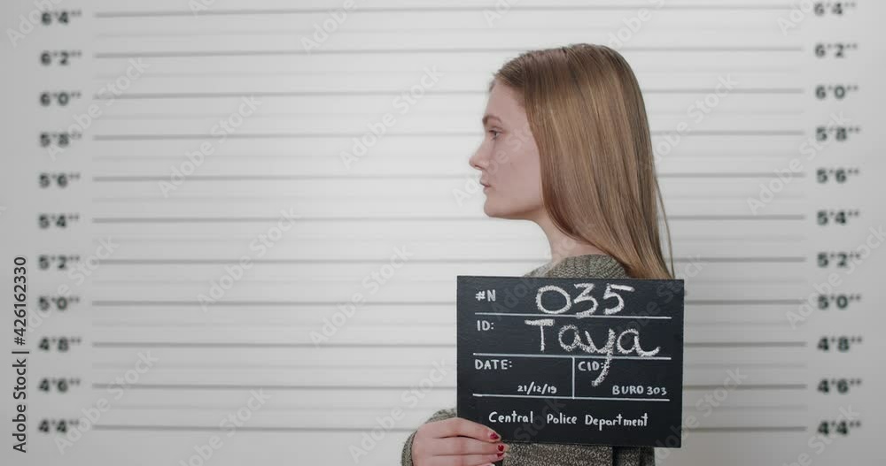 Side profile mugshot of female person holding sign while being ...