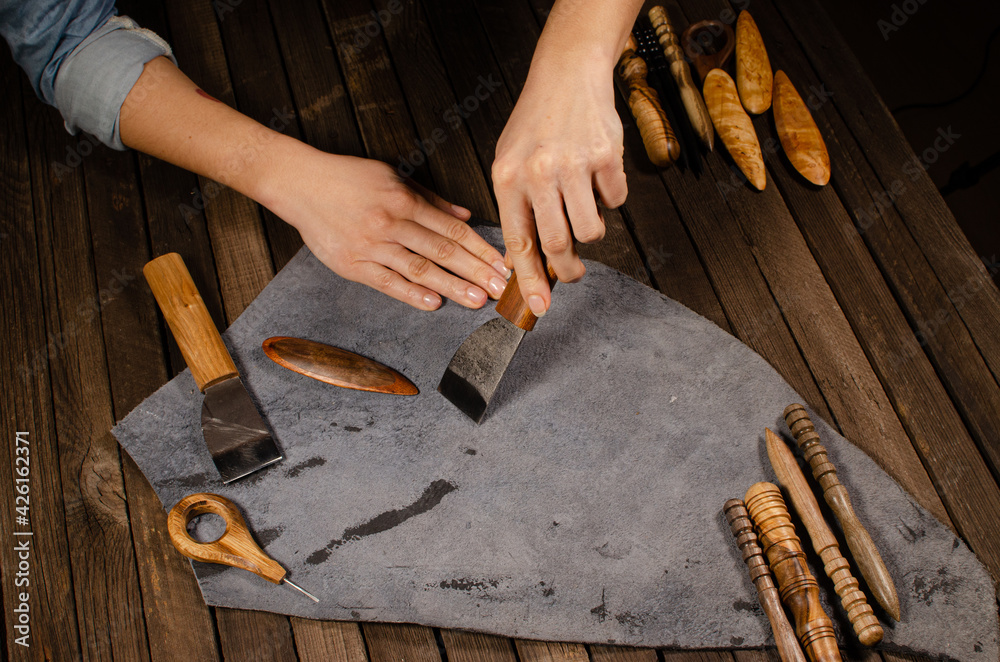 Tilt down of female shoemaker circling stencil lying on piece of brown ...