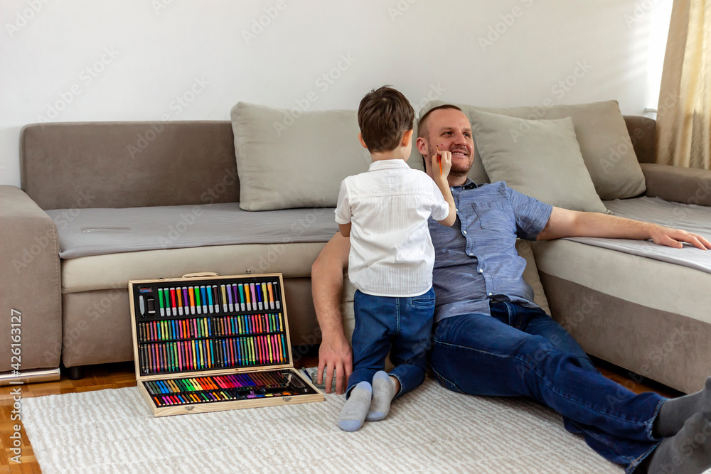 Adorable cute little boy using palette of different colors and painting ...