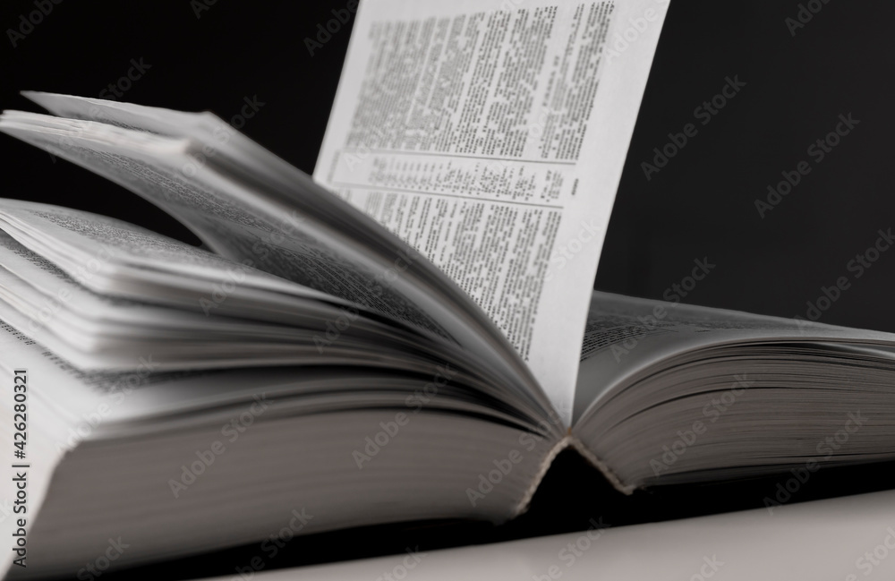 Open book with turning pages. Textbook in hard cover on table ...