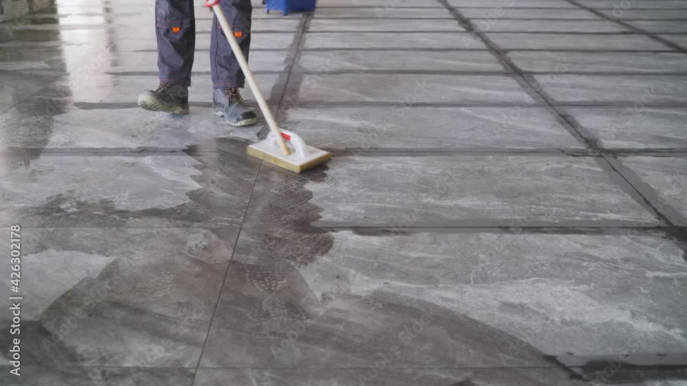 Worker washing tiles after work. A worker washes the tiles on the floor ...