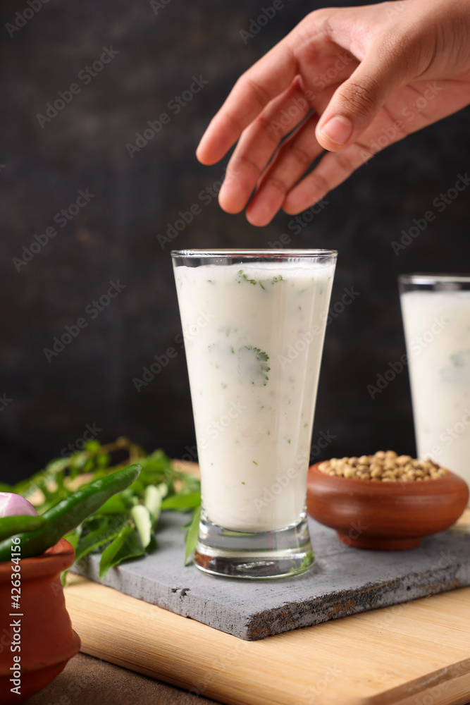 Holding glass of Spiced buttermilk in hand , chaas , chaach , moru ...