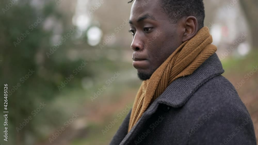 Thoughtful contemplative young black man standing outside in reflection ...