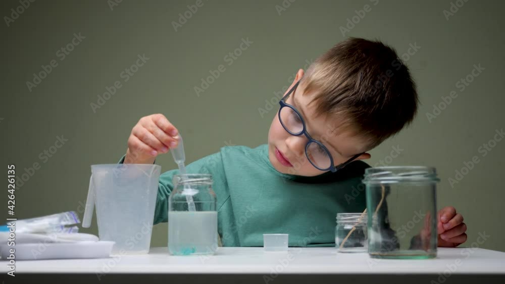 Cute boy use pipette in chemistry lab at pupil table. Child doing ...