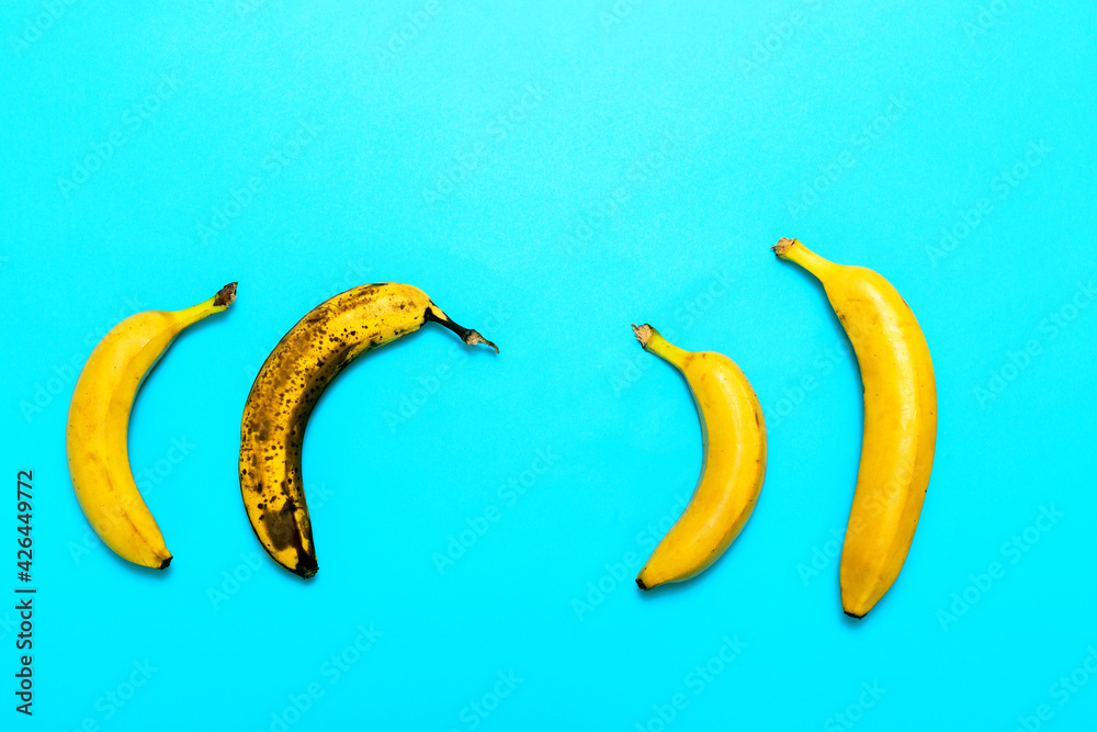 Group of bananas on blue background. Top view. One of the bananas is ...