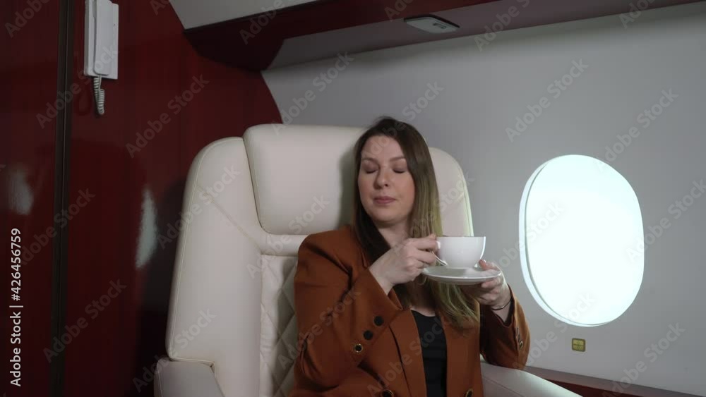 Woman in airplane cabin first business class drinking coffee. Passenger ...