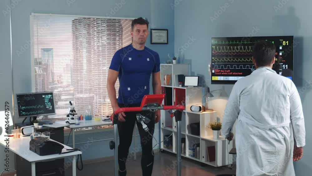 Cardiologist coming to monitor athlete's stress testing on treadmill ...