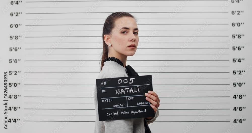 Mugshot of arrested young woman turning head and looking to camera ...
