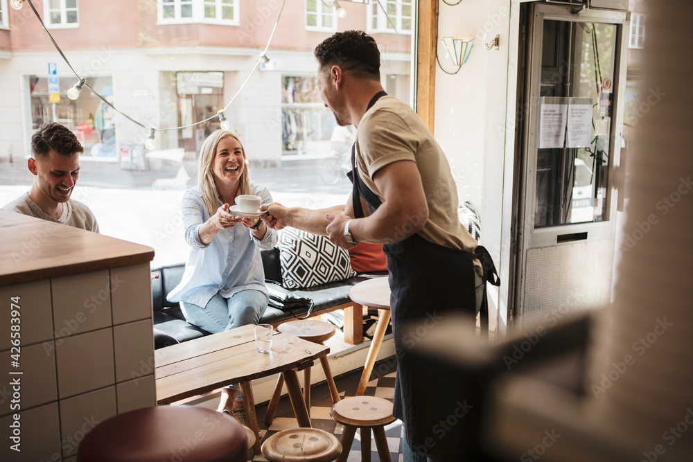 Smiling owner giving coffee to female customer at cafe Stock Photo ...