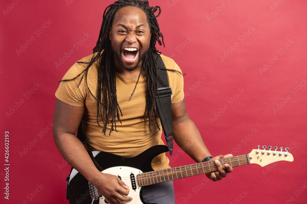 Emotional excited black man playing electric guitar over red background ...