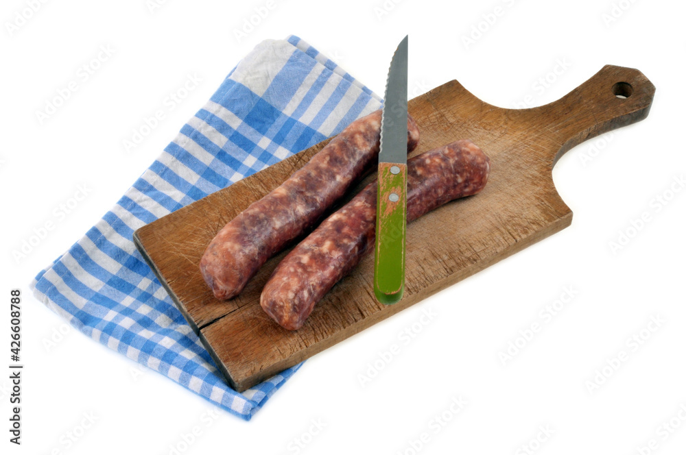 Foto de Saucisses de porc crues sur une planche à découper avec un couteau et un torchon à ...