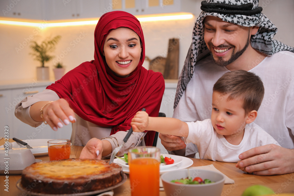 Happy Muslim family eating together at table in kitchen Stock Photo ...