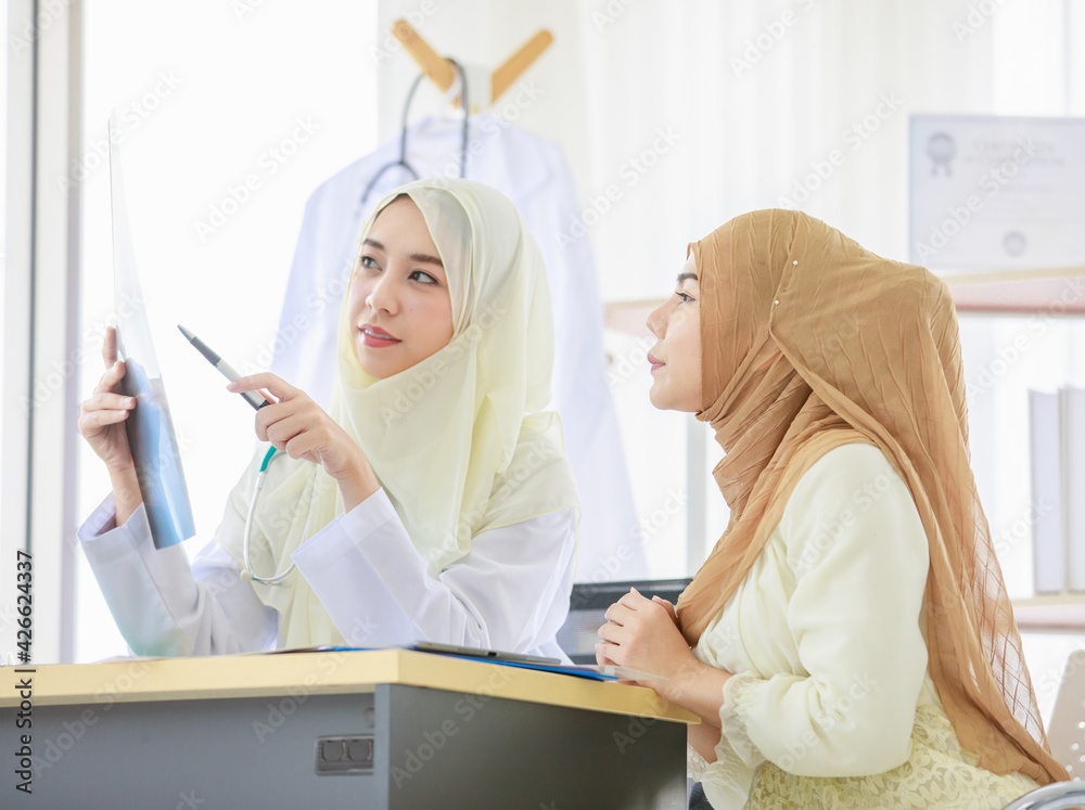 Attractive smiling young adult Muslim doctor wearing cream hijab ...