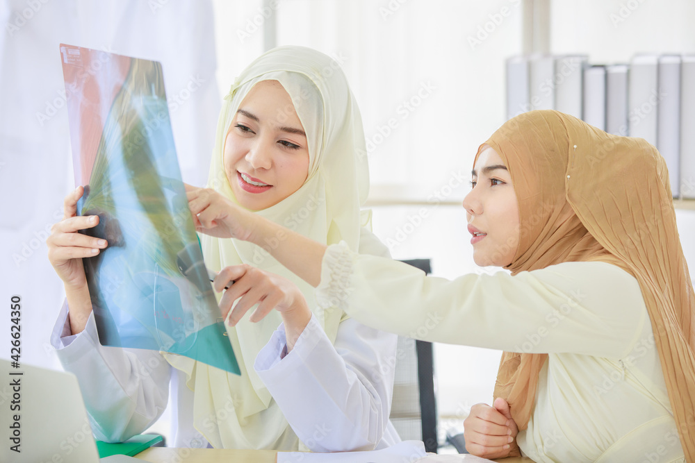 Attractive smiling young adult Muslim doctor wearing cream hijab ...