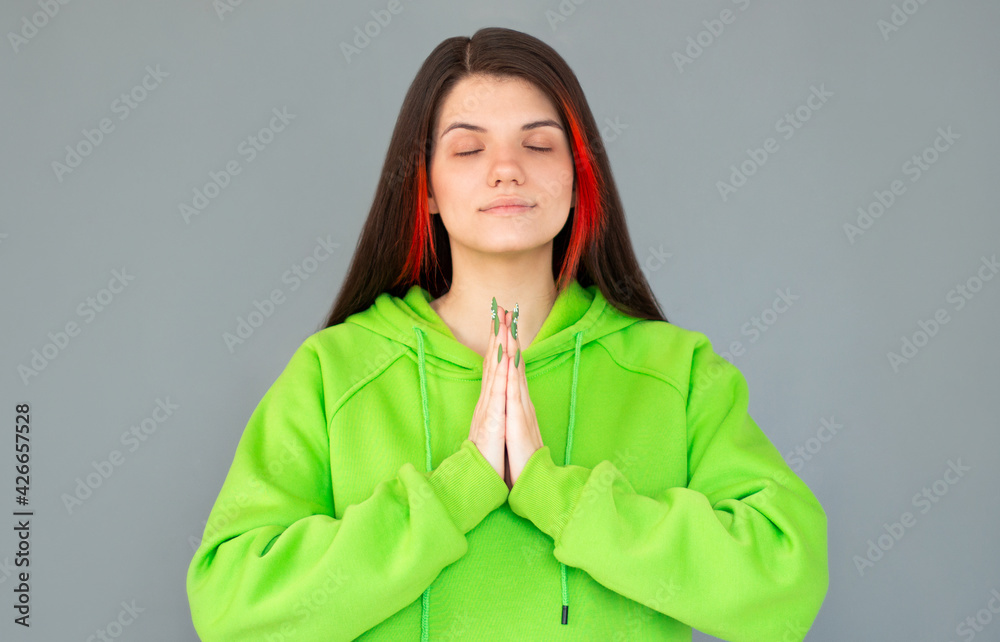 Smiling young woman with closed eyes isolated on gray studio background ...