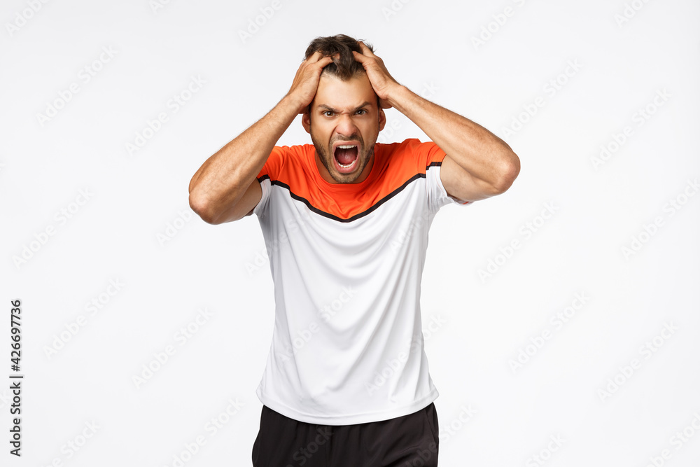 Angry, aggressive mascular sportsman looking furious, grab head in rage ...