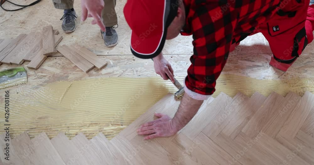 Carpenter worker installing wooden floor, parquet in an apartment ...