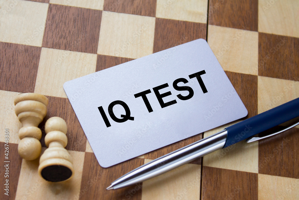 Business card with text IQ Test on a chess board with pen and ...