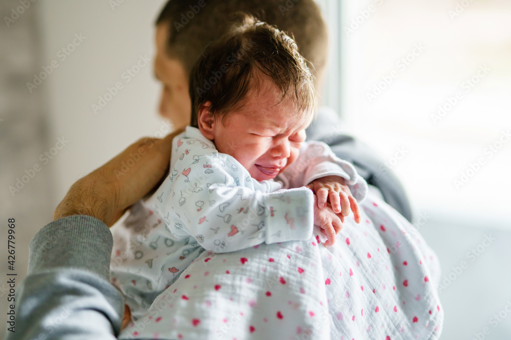 Back view of father holding his newborn baby over the shoulder while ...