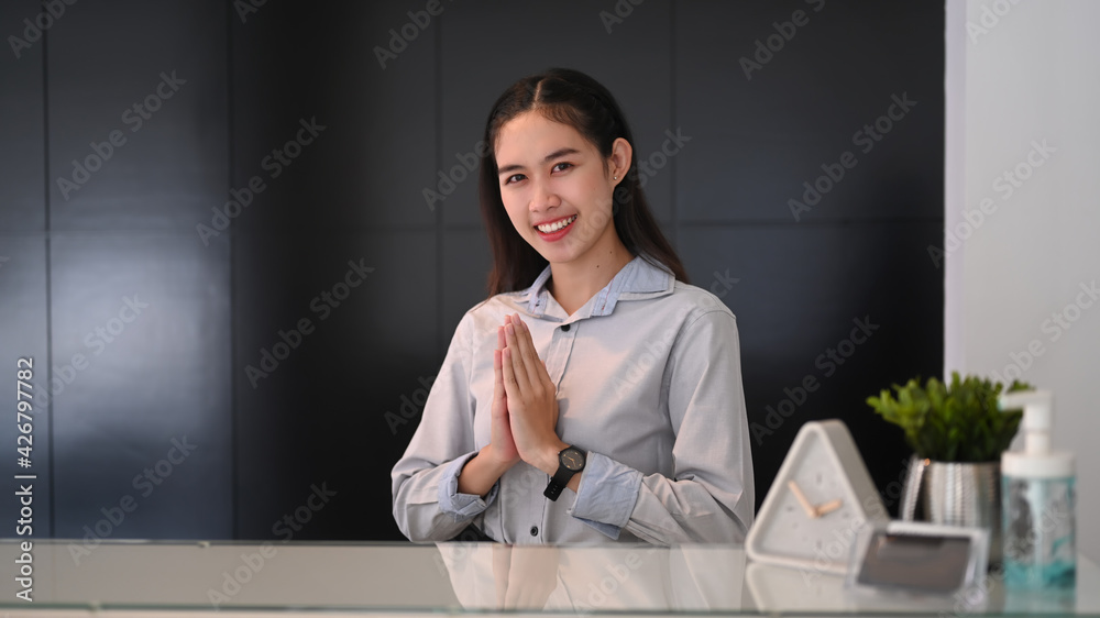 Young asian woman receptionist sitting at reception desk and raising ...