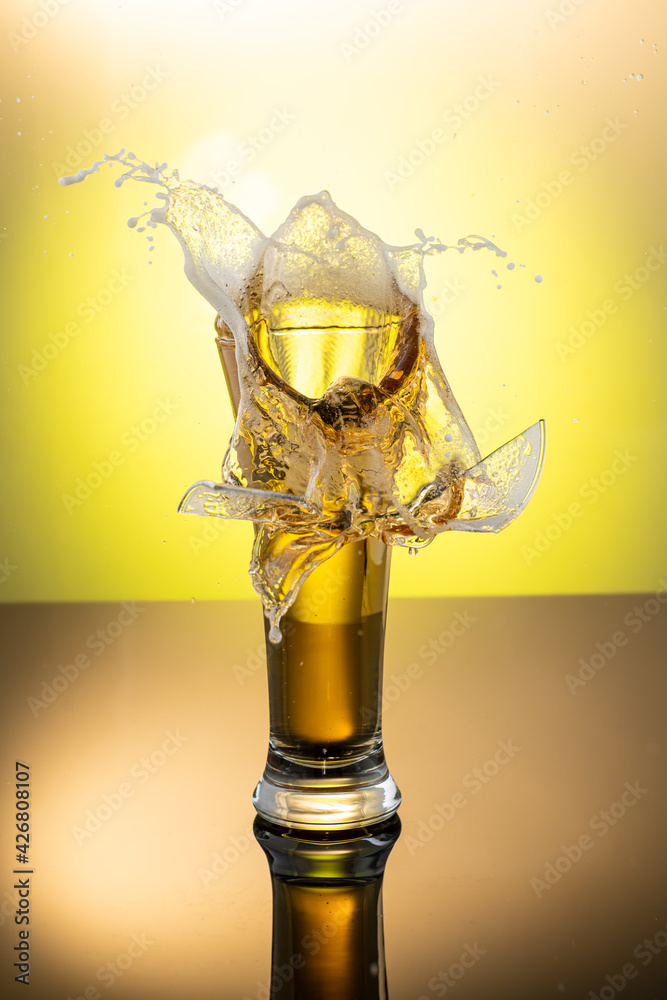 tall transparent glass with beer and a splash from falling ice breaks ...