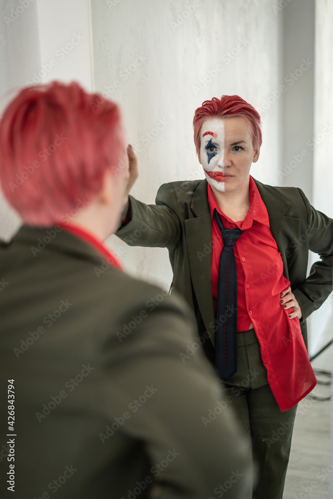 An actress in a clown costume is reflected in the mirror, exactly half ...