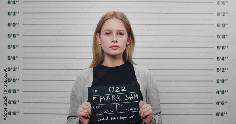 Mugshot of attractive arrested woman holding sign for photo in police ...