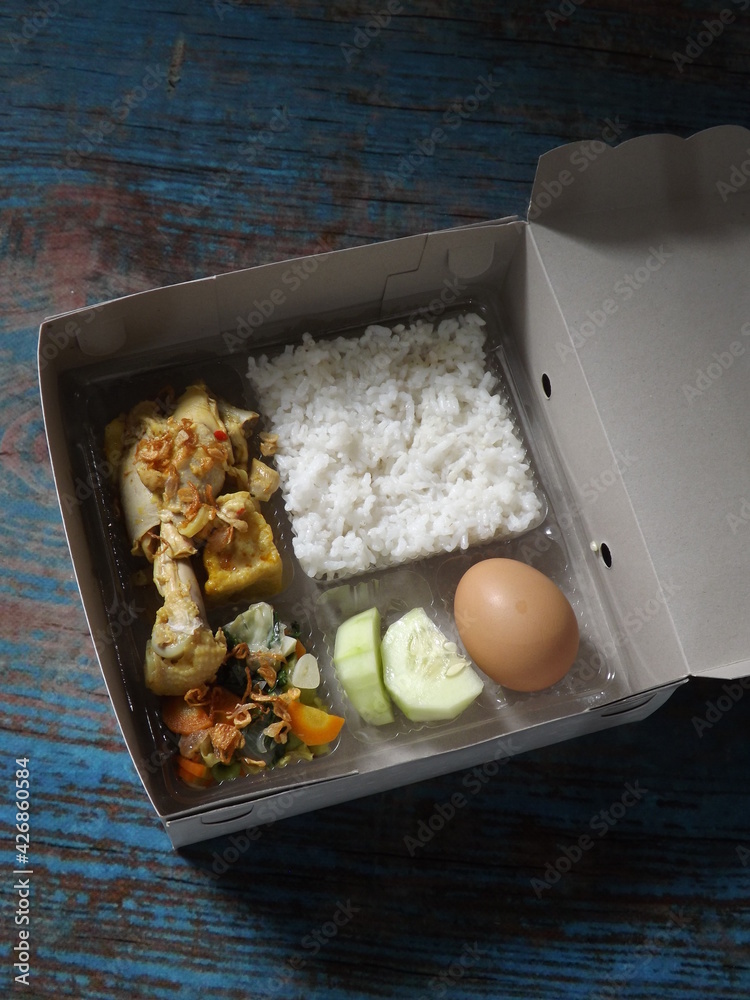 Nasi kotak or Indonesian rice box. Rice, spicy chicken curry, tofu ...