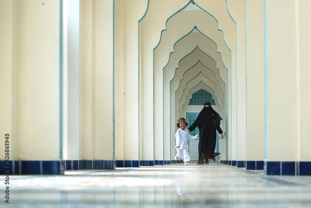Muslim mother and son in traditional suit run together in the corridor ...