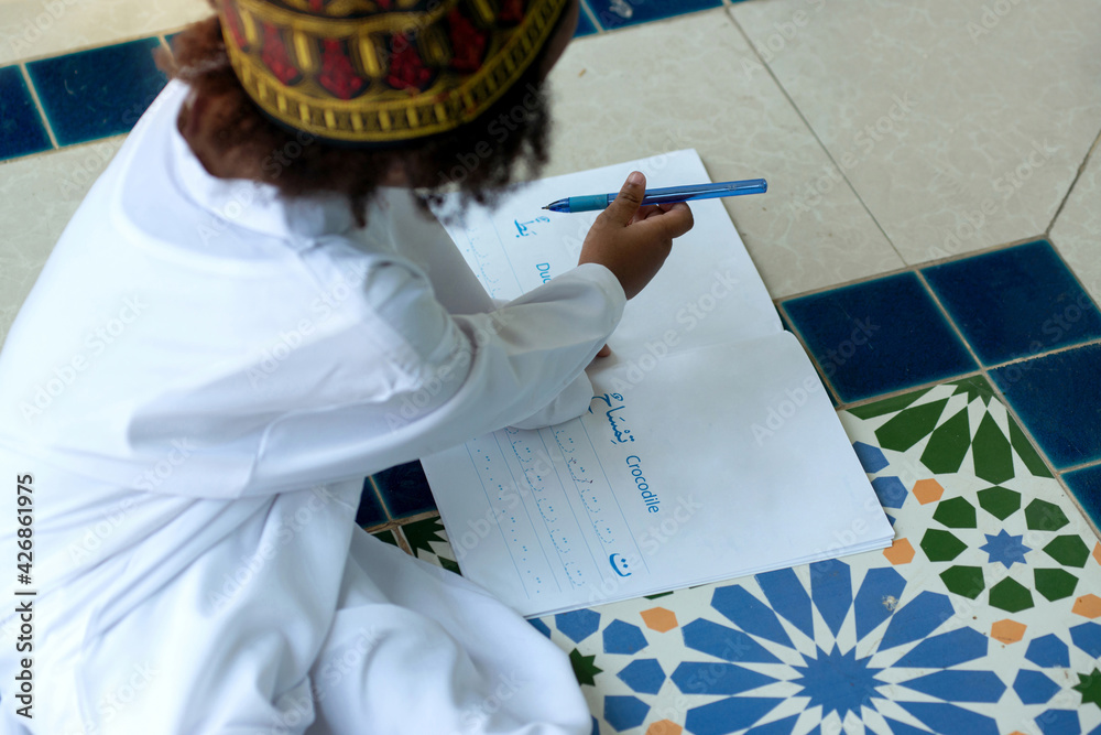 Child boy wearing a traditional Muslim suit learning the Arabic ...