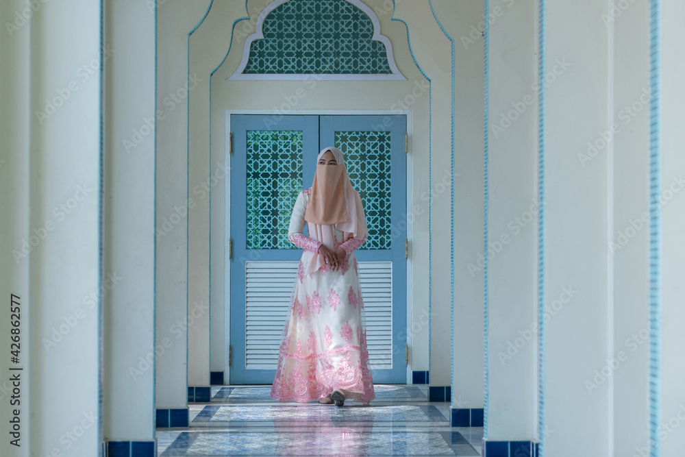 Beautiful Muslim woman in traditional clothing walks in the aisle of ...