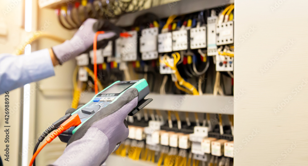 Fotka „Electrical engineer using digital multi-meter measuring ...