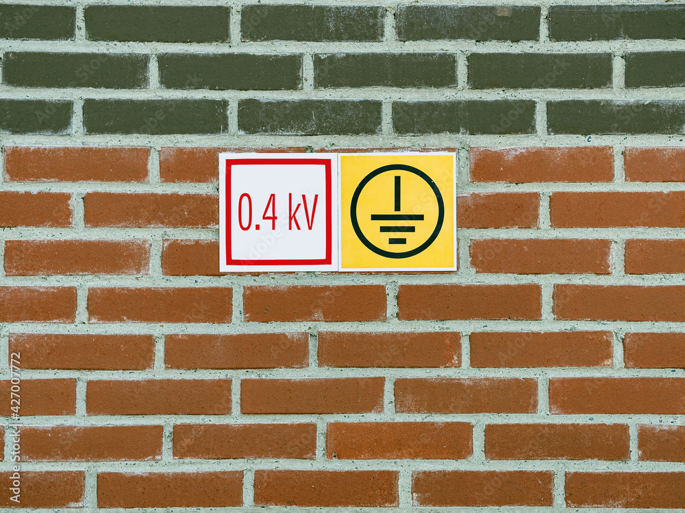 Electrical safety signs on the brick wall of the building. Grounding ...