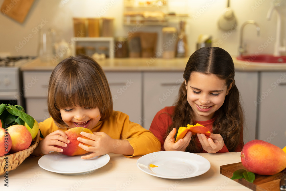 Happy Kids with mango fruit in hands. Cute sisters friends crazy eating ...