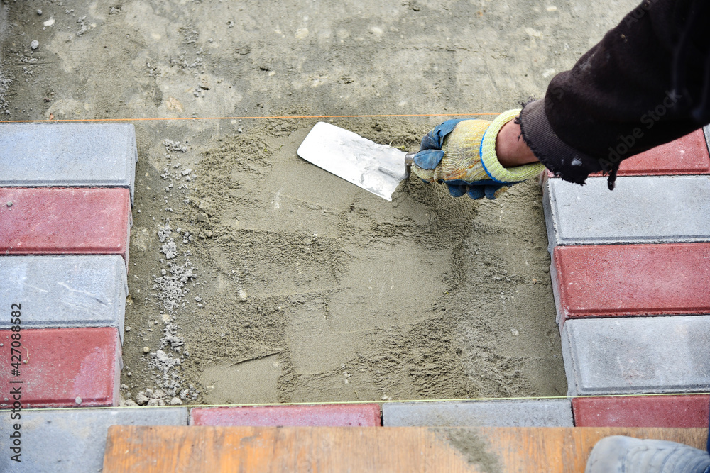 Worker levels the plane with a trowel, laying paving slabs Stock Photo ...