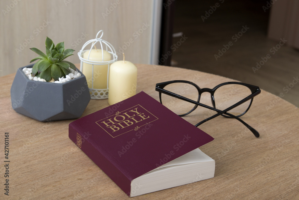 Holy Bible on a round table with candles, plants and glasses. Bible ...