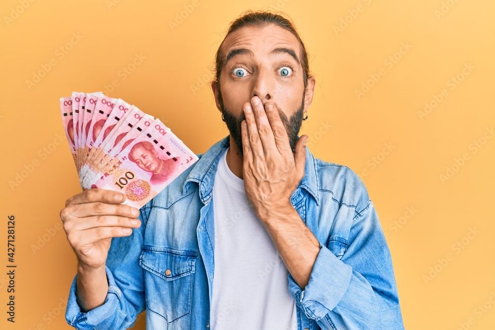 Attractive man with long hair and beard holding 100 yuan chinese ...