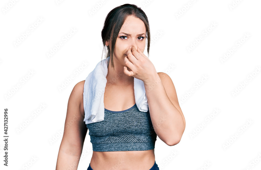 Young hispanic girl wearing sportswear and towel smelling something ...