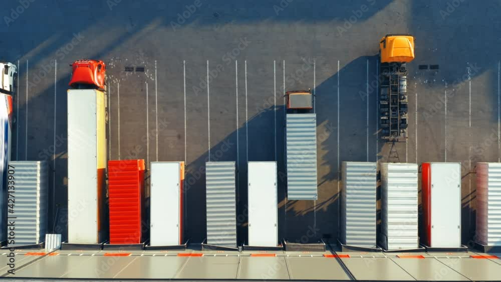 Aerial top down view of a semi-trailer drives up to a warehouse ramp in ...