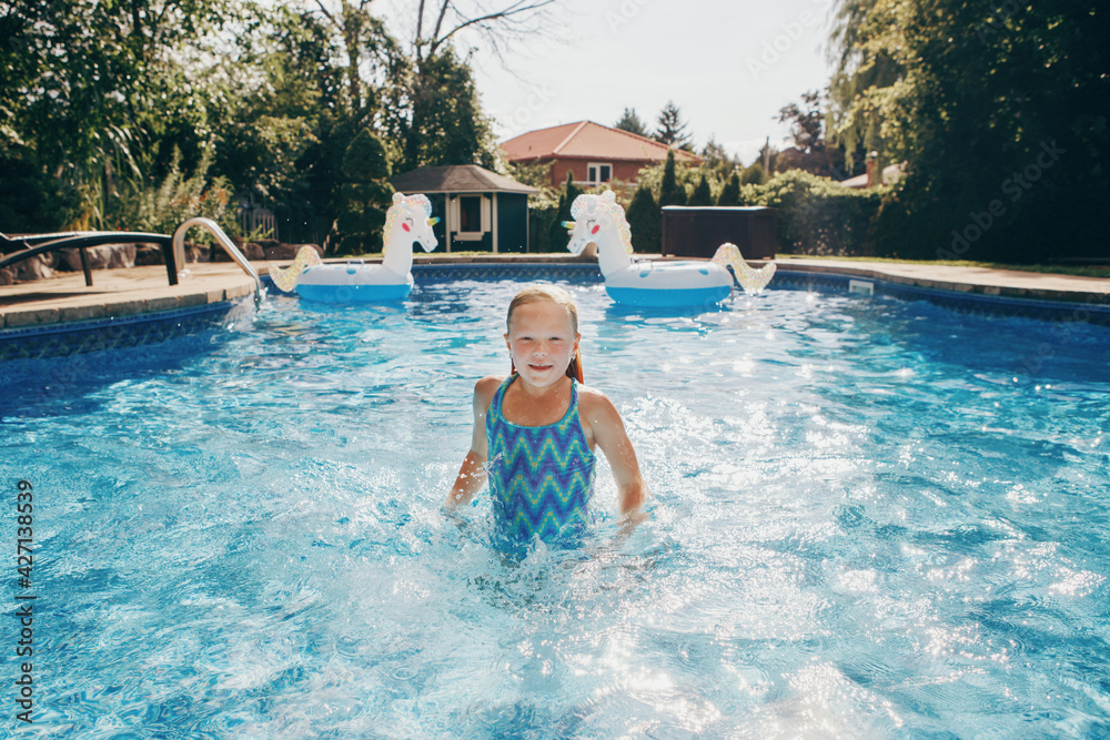 Cute adorable girl swimming in pool on home backyard. Kid child ...