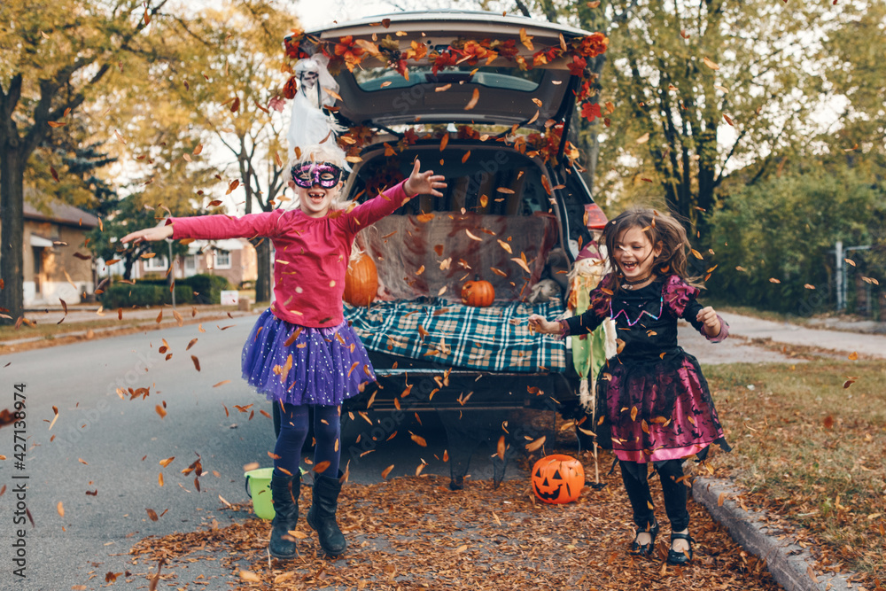 Trick or trunk. Children siblings sisters celebrating Halloween in ...