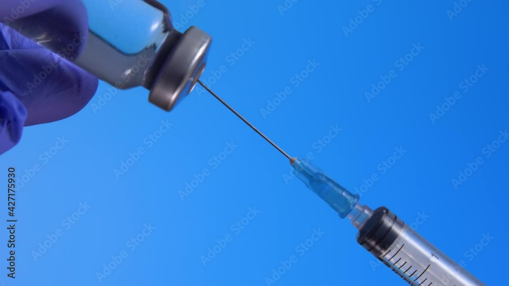 Doctor's hand in blue sterile rubber gloves dials rabies vaccine in ...