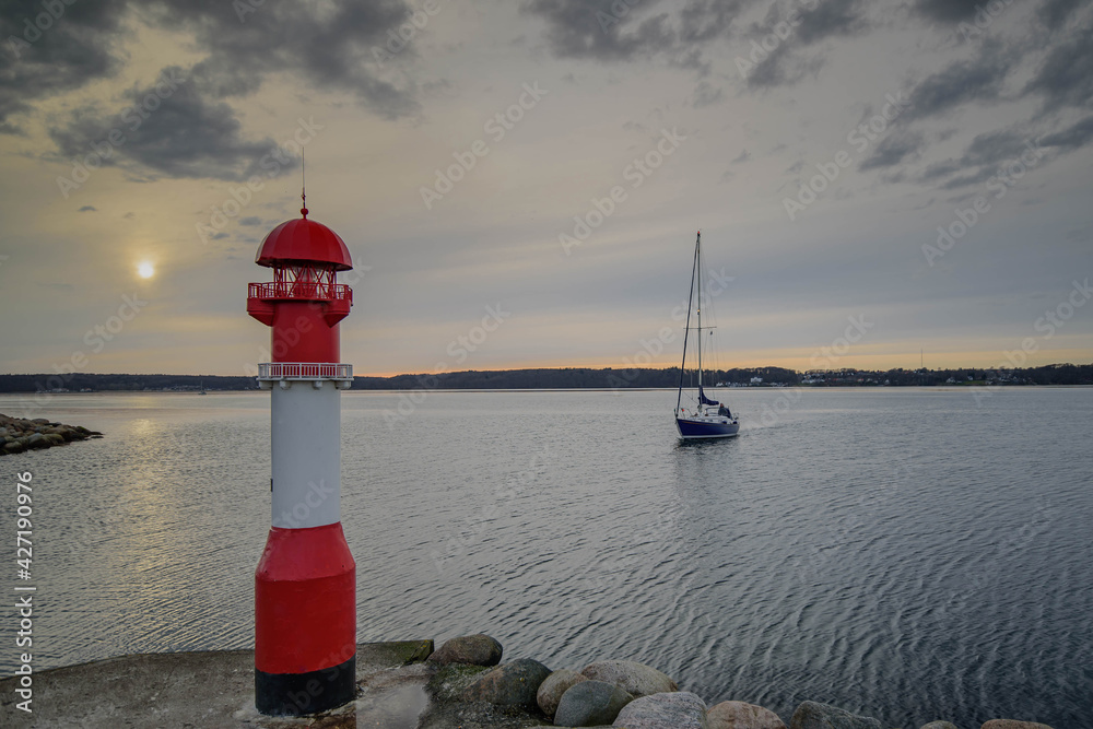 The red pier light with sailing boot enter in marina (dock, basin with ...