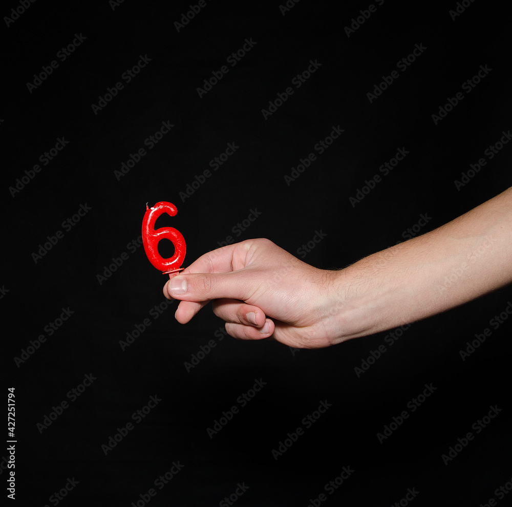 Hand holding up the number 6 against a black background conceptual of ...