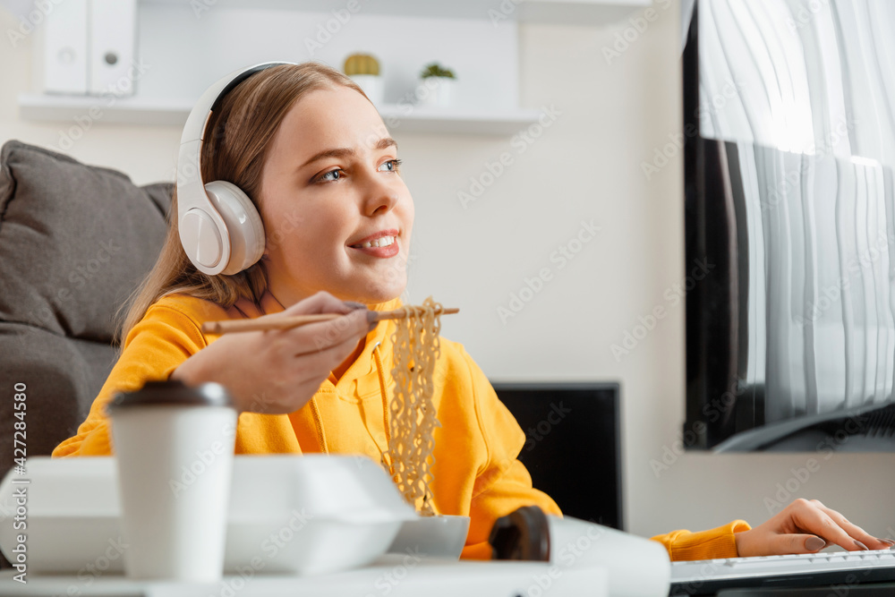Happy woman gamer eats noodles with chopsticks Chinese dish at home ...