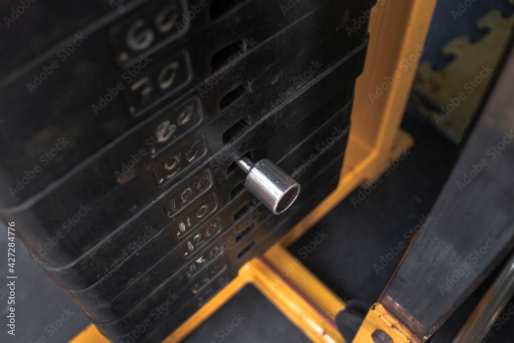 Closeup of a weight stack machine at a gym, with the pin set at the 100 ...
