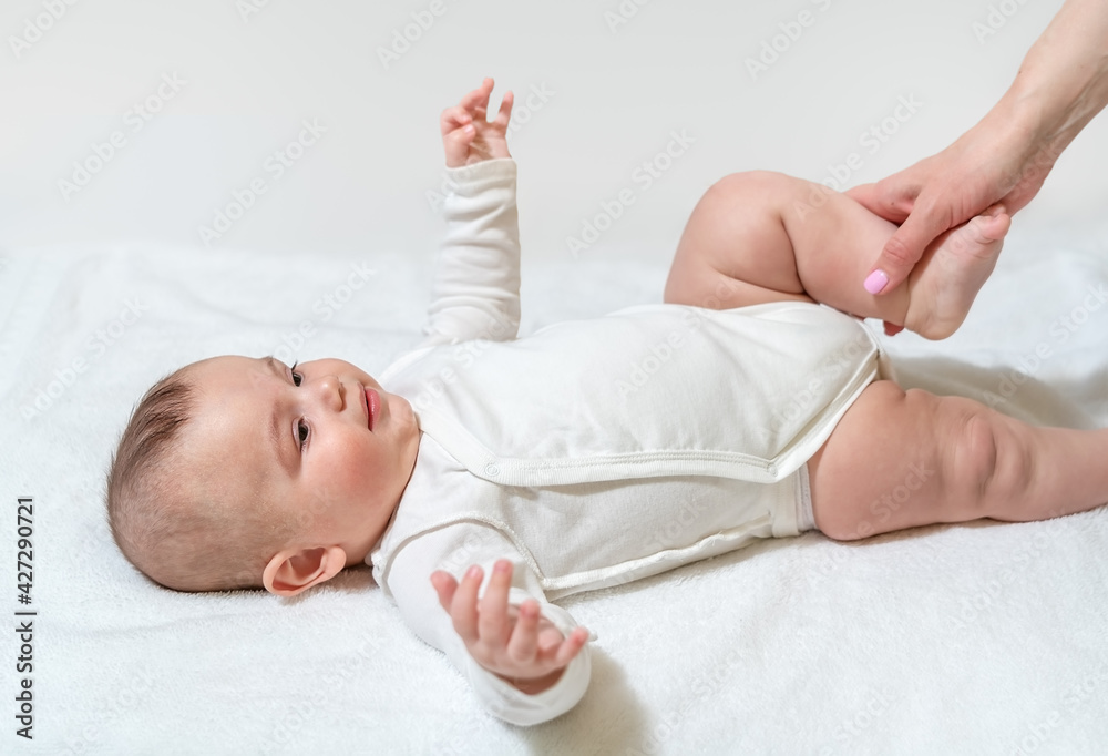 Newborn healthy baby doing physical exercises for the legs and hip ...