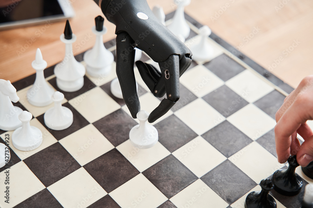 Engineer holding chess piece with black bionic hand while playing at ...