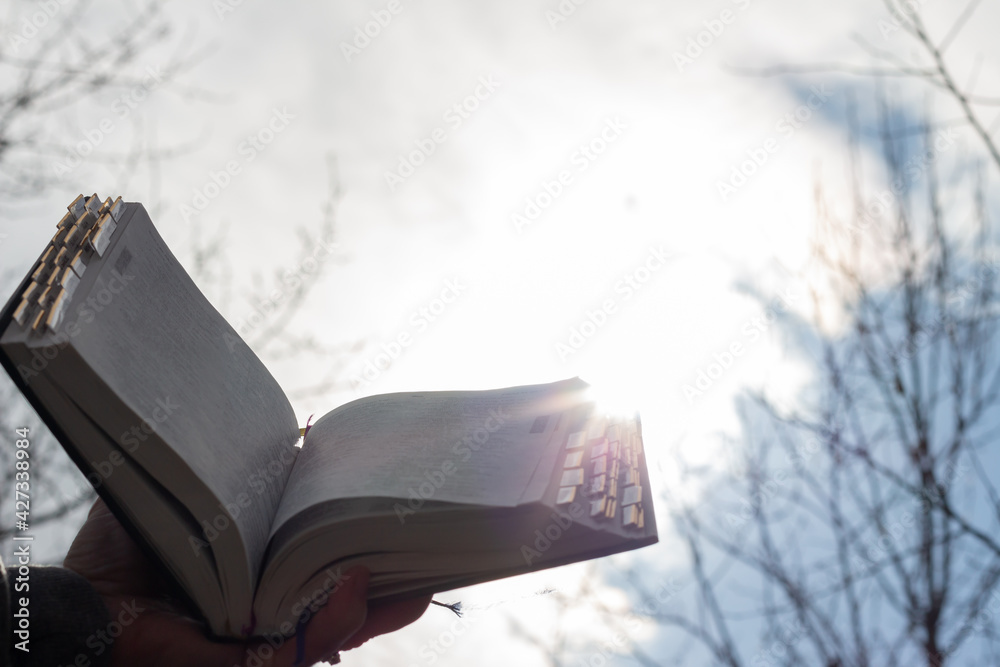 Open bible with sunlight and sky behind Stock Photo | Adobe Stock