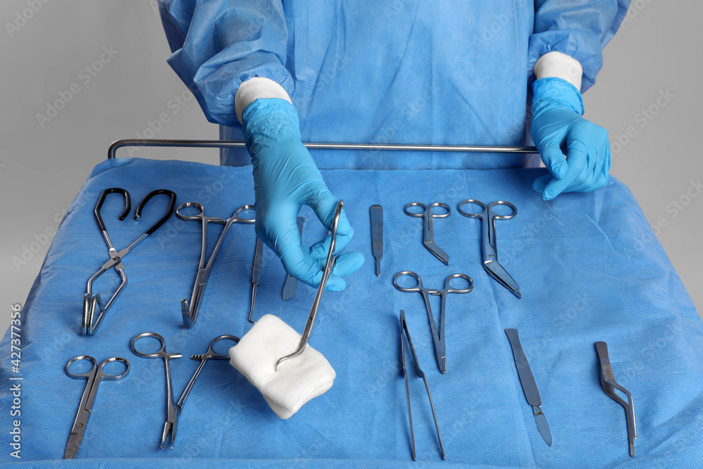 Doctor holding medical forceps with pad near table of different ...